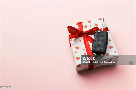 선물 자동차 키 컨셉 탑 뷰를 제공합니다 산호 색 배경에 빨간 리본 활 심장 및 자동차 열쇠가있는 선물 상자 0명에 대한 스톡