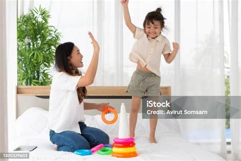 어머니와 딸은 아침에 침대에서 함께 놀고 있습니다 침대에 앉아 어머니와 딸은 홈 검역 중에 함께 게임을 하는 양질의 시간을 즐길 수 있습니다 2명에 대한 스톡 사진 및 기타