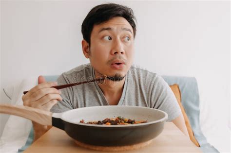 Happy Funny Face Of Man Eating Homemade Food In The Pan With Chopsticks