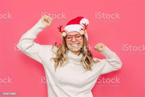 흰색 따뜻한 스웨터와 빨간 산타 모자를 쓴 한 젊은 여성이 손을 들고 기뻐합니다 크리스마스와 새해 컨셉 크리스마스에 대한 스톡 사진 및 기타 이미지 Istock