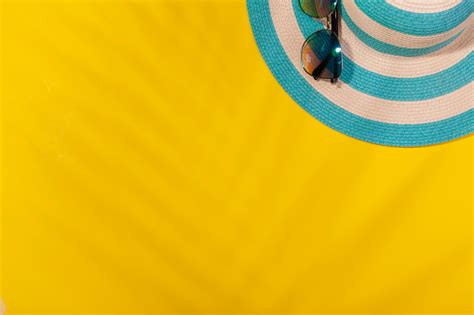 노란색 배경의 해변 액세서리의 상단 보기 선글라스와 야자잎 그림자줄무늬 파란색 모자 해변 휴가 바다 투어 따뜻한 화창한 여름의 개념 광고 공간 개념에 대한 스톡 사진 및