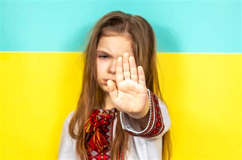 우크라이나 국기의 배경에 대해 그녀의 손을 잡고 국가 우크라이나어 옷을 입은 소녀 자수 셔츠 우크라이나에서 전쟁을 중지합니다 전쟁에 반대하는 아이들 가린 얼굴에 대한 스톡