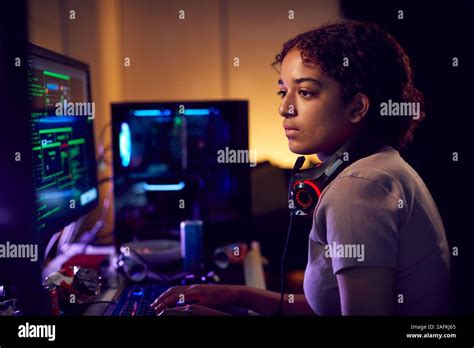 Female Teenage Hacker Sitting In Front Of Computer Screens Bypassing