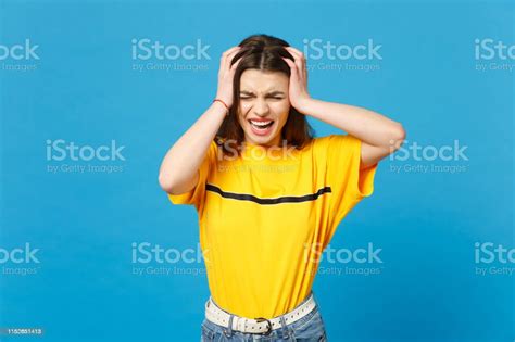 스튜디오에서 파란색 벽 배경에 고립 된 머리에 손을 넣어 눈을 감고 생생한 캐주얼 복장에 비명 젊은 여자 좌절의 초상화 사람들