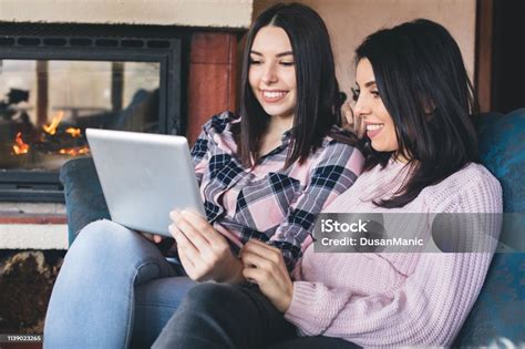 젊은 여자 친구는 벽난로 근처에 앉아서 태블릿을 보고 2명에 대한 스톡 사진 및 기타 이미지 2명 가정 생활 가족