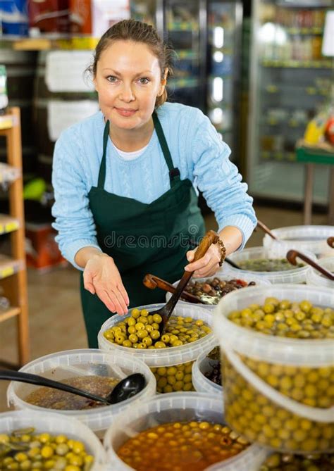 Middle Aged Saleswoman Showing Olives In Grocery Store Stock Image