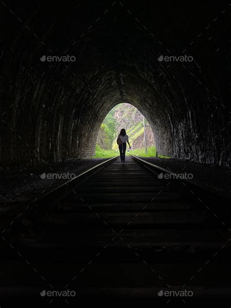 Girl Walking Through A Dark Tunnel To The Exit Light At The End Of The Tunnel Stock Photo By