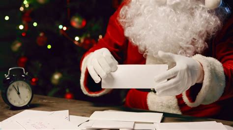 دانلود فوتیج ویدیویی بابا نوئل با تزئینات کریسمس پشت میز نشسته در اتاقی