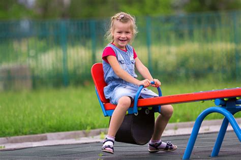 작은 귀여운 젊은 금발의 아이 소녀는 밝은 녹색 흐린 배경에 따뜻한 화창한 날에 그네를 보았다에 앉아있다 어린 시절의 기쁨과