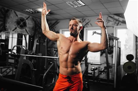 강한 젊은 보디 빌더는 체육관에서 운동을하는 근육질의 보디 잘 생긴 남자처럼 보입니다 프리미엄 사진