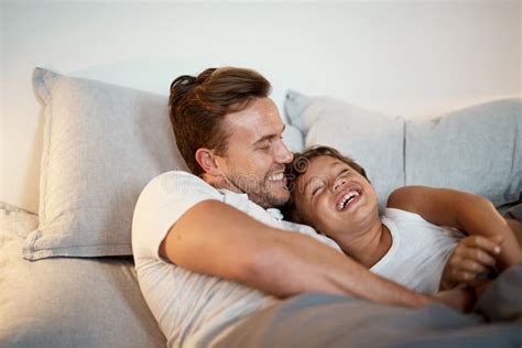 Ill Just Have To Tickle You To Sleep A Man And His Son Lying In A Bed