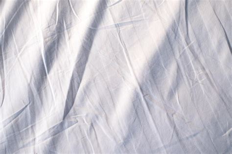 추상 럭셔리 패브릭의 흰색 침대 린넨 그라데이션 질감 흐릿한 곡선 스타일주름이 있는 침대 린넨과 짙은 회색 그림자 배경