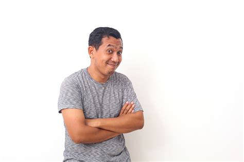 팔을 건널 때 재미있는 얼굴로 서있는 아시아 남자의 초상화 복사 공간이있는 흰색 배경에 격리 됨 T 셔츠에 대한 스톡 사진 및