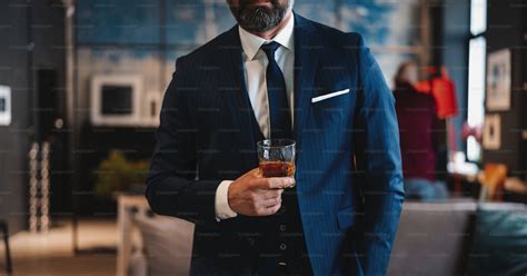 성숙한 잘 생긴 사업가는 서서 자신의 사무실에서 위스키 한 잔을 들고 있습니다 사진 Unsplash의 사무실 이미지