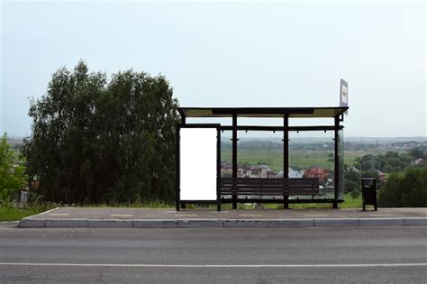건물과 도로가 있는 거리 배경의 버스 정류장에 있는 수직 흰색 광고판 프리미엄 사진