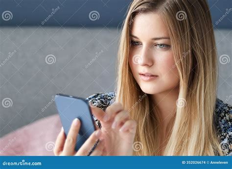 Woman With Long Blonde Hair And Blue Eyes Looking At Her Smartphone