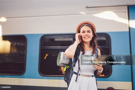 테마 관광 및 여행 젊은 학생 아름 다운 젊은 백인 여자 드레스와 모자에 서 기차 역 근처에 배낭과 컵 커피 손에 스마트폰 전화 기술 사용 개념에 대한 스톡 사진 및 기타