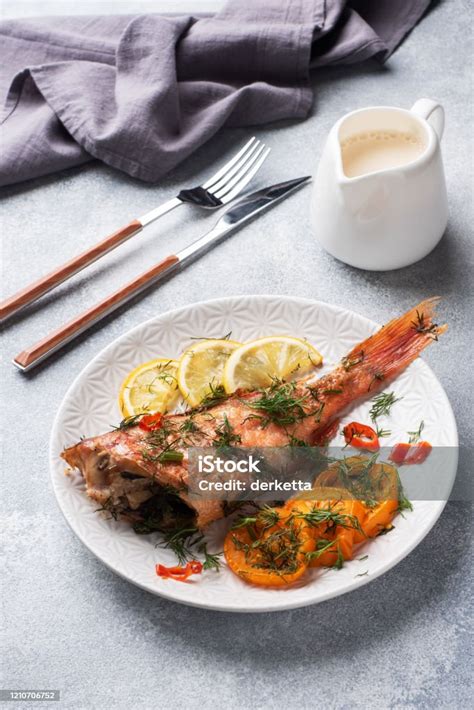 회색 콘크리트 배경에 세라믹 접시에 토마토 후추 레몬과 허브와 구운 농어 오븐에서 조리한 농어 생선 0명에 대한 스톡 사진 및