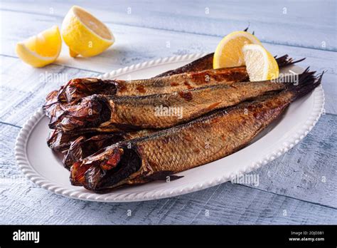 A Plate Of Delicious Smoked Herring Kippers With Lemon On A Wood Table