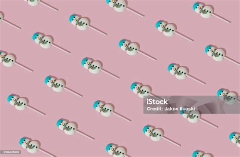 파스텔 핑크 배경에 눈사람 롤리팝으로 만든 크리스마스 패턴입니다 최소한의 크리스마스와 새해 달콤한 사탕 개념입니다 창의적인 축제 휴가 아이디어 겨울의 미적 배경 0명에 대한