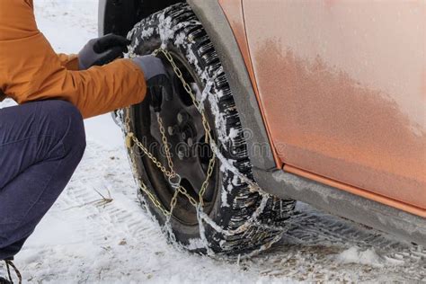 Driver Installs Chains On The Wheel Of His Car In Winter Vehicle