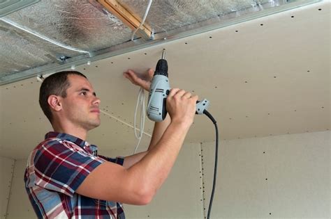 Premium Photo Worker Fixing Drywall To Ceiling