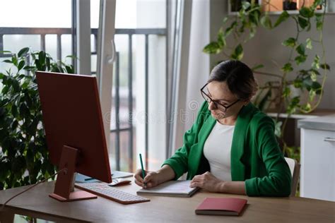 Focused Caucasian Woman Tutor Or Teacher Making Notes In Notebook Sits