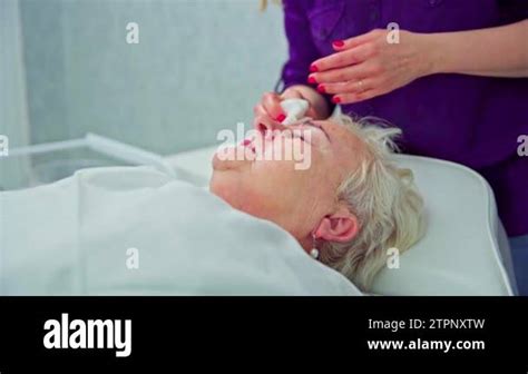 A Blonde Woman With Short Hair Is Lying On A Bed In A Beauty Salon She Is Covered With A White