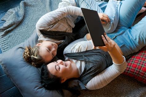 Premium Photo Happy Two Sisters Using Tablet While Lying On Their
