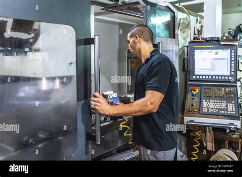Rear Side View Of A Male Caucasian Adult Technician Using Milling Machine Commands In A Cnc