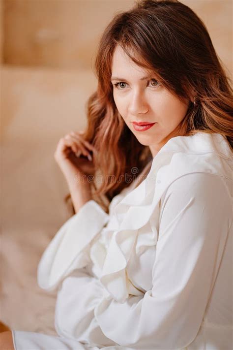 A Beautiful Woman In A White Dress With Lacing And Ruffles Sits On The