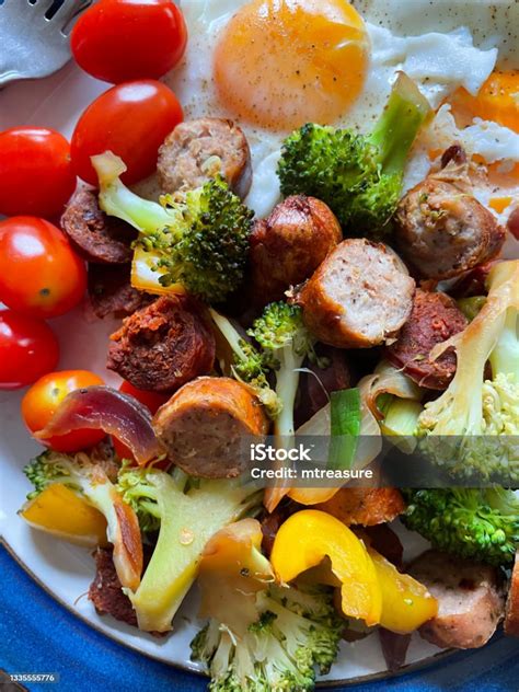 소시지와 야채 볶음요리 붉은 다진 양파 초리조 소시지 슬라이스 브로콜리 꽃 노란 피망 덩어리가 들어 있는 블루 테두리 접시의 풀 프레임 이미지 체리 토마토와 계란 튀김 높은