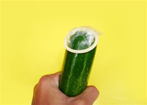 Um Homem Segura Um Pepino Com Um Preservativo Em Fundo Amarelo Com