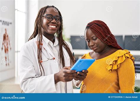 African American Women Doctor And Patient Using Touchpad Having