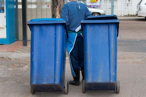 Premium Photo Man With Garbage Bin Against Blue Wall
