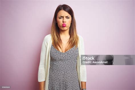 젊은 아름다운 여자 는 재미있는 얼굴과 분홍색 고립 된 배경 퍼핑 뺨 위에 서있다 공기 미친 표정으로 입이 팽창 가득 찬에 대한