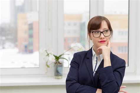 그녀의 직장에서 사무실에서 창에 의해 파란색 재킷과 안경을 입고 세련된 예쁜 비즈니스 여성은 작업이 완료된 것에 만족합니다 30 34세에 대한 스톡 사진 및 기타 이미지
