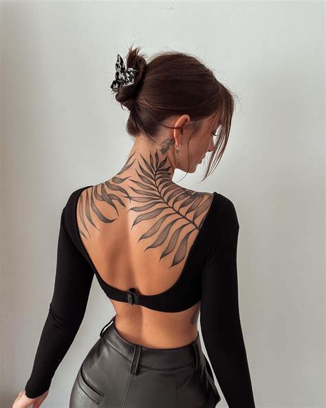 The Back Of A Woman S Body With Tattoos On Her Upper And Lower Half