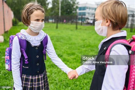 얼굴에 안전 보호 마스크와 작은 귀여운 여자 여학생 준비 학교에 가서 야외에서 배낭을 가진 어린 자매 학교로 돌아갑니다 코로나