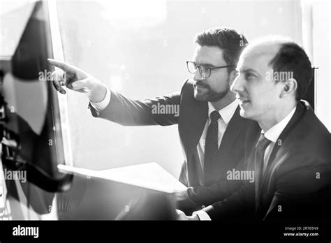 Image Of Two Thoughtful Businessmen Looking At Data On Multiple