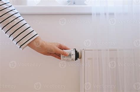 Woman Regulates Temperature At Home With The Heating Thermostat To Save Energy Close Up With