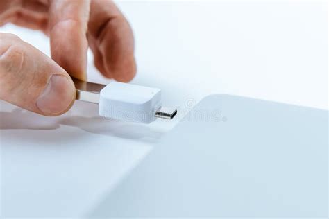 Male Inserts A Compact USB Card Into The Corresponding Input In The Side Of The White Netbook
