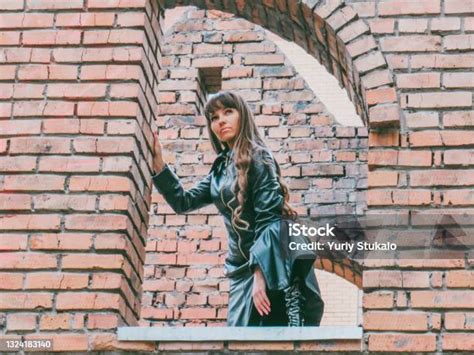 벽돌 건물의 창문 개구부에서 검은 가죽 비옷을 입은 아름다운 여성 가죽에 대한 스톡 사진 및 기타 이미지 가죽 드레스 개인 장식품 Istock