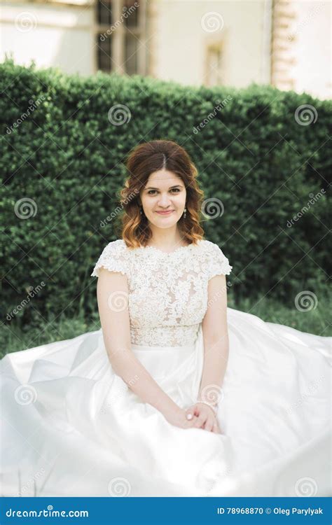 Beautiful Brunette Bride In Elegant White Dress Holding Bouquet Posing