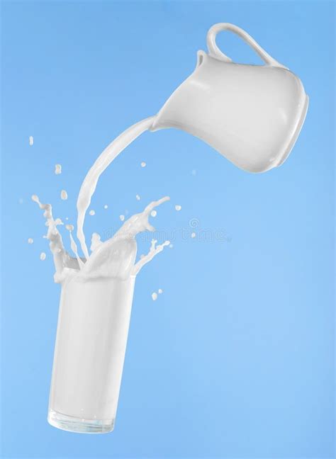 Pouring Milk From Jug Into Glass Cup With Splashing On Blue Background