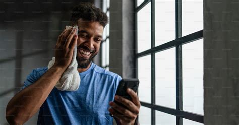 행복한 젊은 아프리카계 미국인 스포츠맨이 체육관 실내에 서서 스마트폰을 사용하고 있다 사진 Unsplash의 브랜드 이름