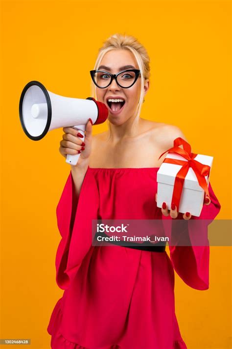 빨간 드레스를 입은 금발 소녀가 메가폰을 들고 있는 선물과 노란 배경에 손에 선물 상자를 들고 있는 것에 대해 이야기합니다 18