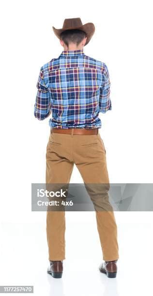 3039세 성인 잘생긴 3039세 성인 잘생긴 남자의 전신 카우보이 부츠 카우보이 모자 모자를 쓰고 흰색 배경 앞에 서 있는 카우보이 진지한 자신감 집중력의 후면보기 30