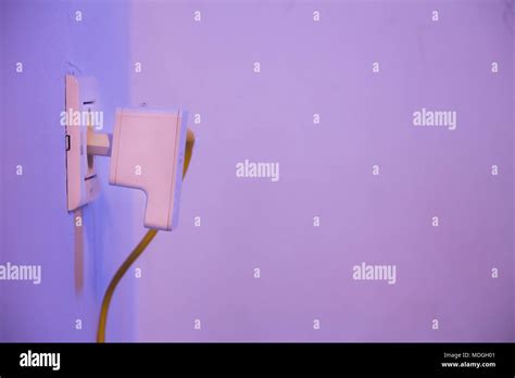 Wifi Extender In Electrical Socket On The Wall With Ethernet Cable Plugged In The Device Is In