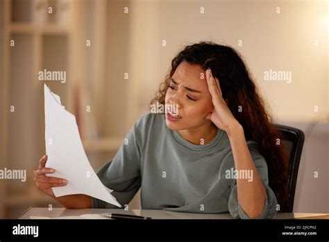 Young Woman Looking Stressed While Going Through Paperwork Alone In An